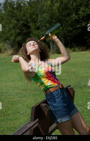 Teenage girl drinking alcohol on a park bench Stock Photo - Alamy