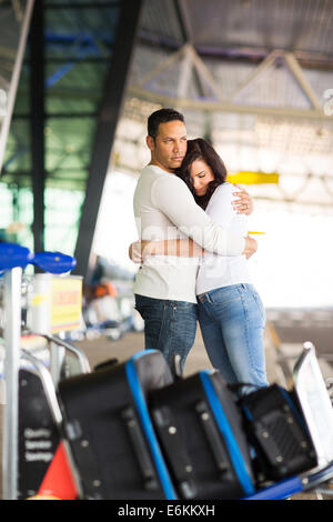 Couple, hug and embracing goodbye at airport for travel, trip or flight ...