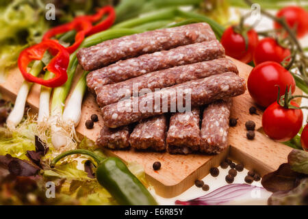 raw kebapcheta with vegetables on wooden board, selective focus Stock ...