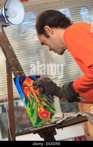 Man with Aspergers painting in his art studio and holding his paint ...