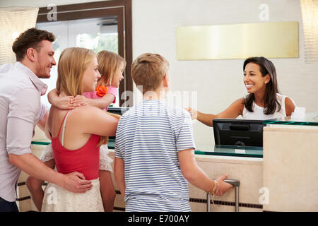 Happy family checking in hotel at reception desk Stock Photo - Alamy