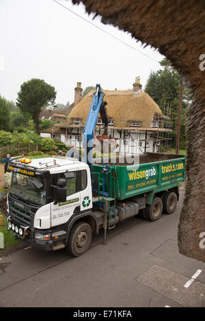 A grab truck with crane in action loading bricks and paving. Waste ...