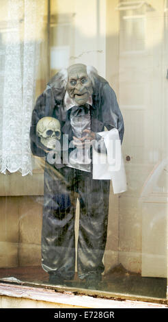 Scary butler stood in old hotel foyer holding human skull Stock Photo ...