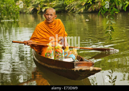 Thai buddhist monk rowing boat early in the morning at amphawa floating ...
