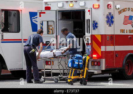 Paramedics loading stretcher into ambulance Stock Photo - Alamy
