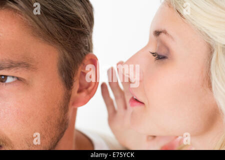 A young woman whispering into a man's ear Stock Photo - Alamy