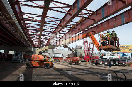 Iron Workers on a lift platform get ready to attach new steel beams for ...