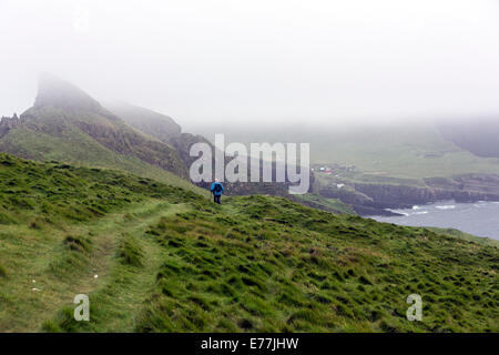 Hiking people towards Mykines village in a misty afternoon Stock Photo ...