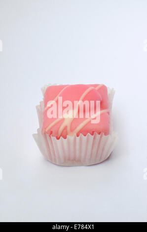 Pink fondant icing on sponge cakes set on a pastel pink background ...