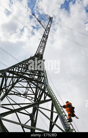 Overhead transmission cable installer climbing a mast to install ...