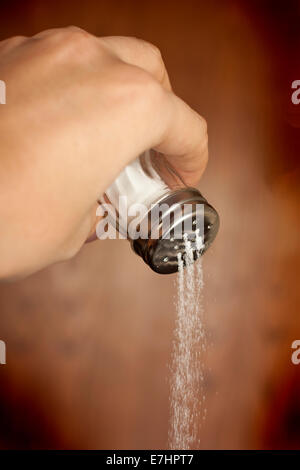 Hand adding salt using salt shaker on bright background Stock Photo - Alamy