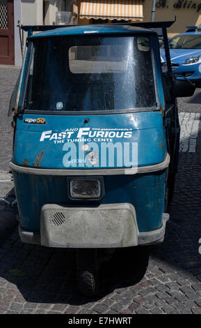 A blue Italian Ape three wheeled utility vehicle approaches along a ...