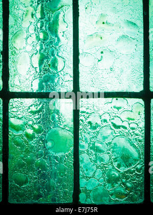 Green stained glass window with regular block pattern as background ...