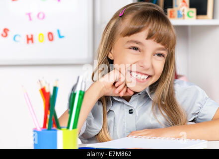The little girl is doing homework happily and smile. Children use a ...