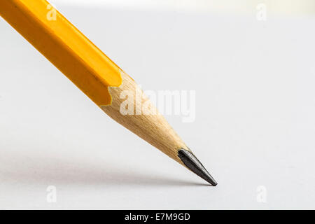 A sharpened yellow pencil over a blank sheet of paper with a broken tip ...
