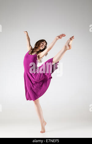 Young ballet dancer wearing purple dress over grey Stock Photo - Alamy