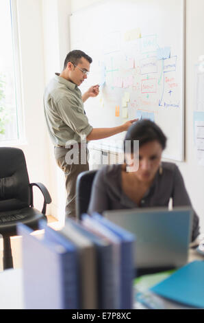Man and woman business workers writing on cork board at office Stock ...