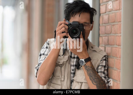 Male photographer photographing through camera against room with ...