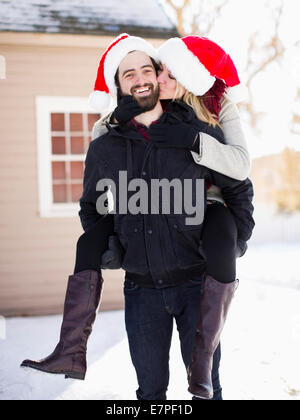 Young couple in Santa hats with cups of cocoa on red background Stock ...