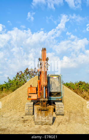 Mechanical digger on an earth mound with earth carrying conveyor belt ...