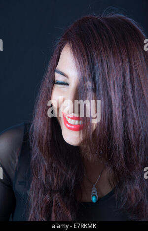 A happy woman with long dark hair, wearing a blue and white striped ...