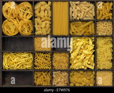 Wooden boxes with different types of uncooked pasta on color background ...