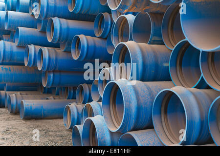 Large diameter plastic pipes lay stacked, ready for use, in the storage ...