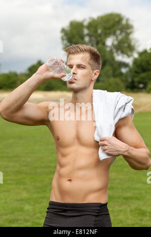 Keeping hydrated. A fit young man taking a water break while exercising ...