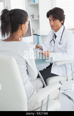 Doctor taking notes from patient Stock Photo - Alamy