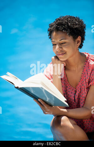 WOMAN READING BOOK BY SWIMMING POOL Stock Photo - Alamy