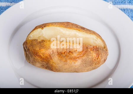 A hot baked potato on a white plate and wood table Stock Photo - Alamy