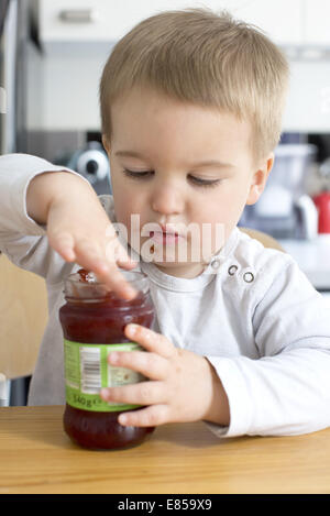 Boy eating jam from jar Stock Photo - Alamy