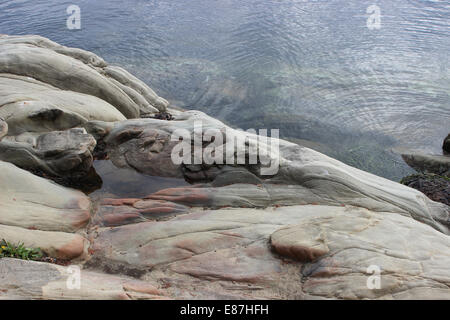 Rocks shaped and smoothed by the ocean are in an arrangement on a large ...