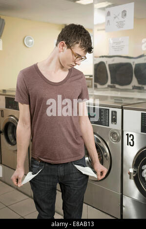 Young man pulling his empty pockets Stock Photo - Alamy