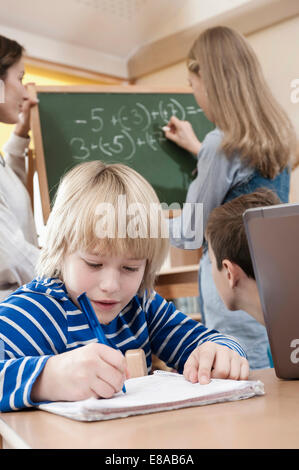 Female childcare assistant helping children by doing homework Stock ...