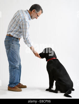 Man feeding cute dog with food from metal bowl Stock Photo - Alamy