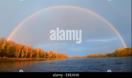 The beautiful rainbow over a tranquil river surrounded by green ...