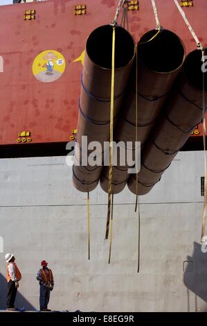 Workers Offloading Pipe from Cargo Ship Stock Photo - Alamy