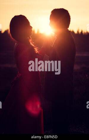 Silhouette of a young couple in love at sunset next to a field of ...