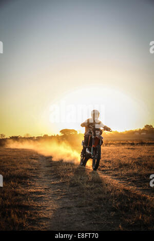 Man riding motorcycle creating dust trail Stock Photo - Alamy