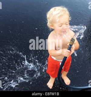 Cute boy drinking water on light background Stock Photo - Alamy