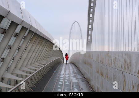 Woman in red walking on sandy beach on the Baltic Sea in gloomy weather ...