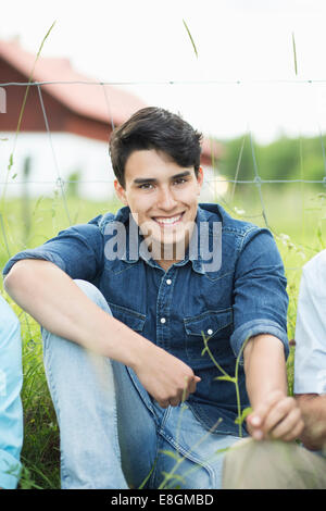Portrait of a joyful young man sitting on chair and holding money cash ...