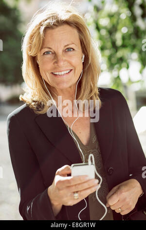 Businesswoman listening to music through wireless headphones sitting ...