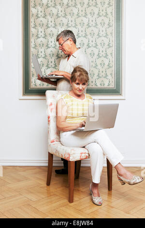 Middle aged woman surfing internet on laptop typing on keyboard ...