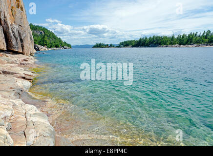 A high cliff on the shore of a lake with colorful clouds in the sky at ...