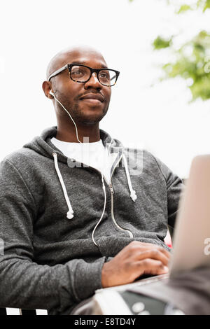 Happy black man using laptop and wireless headphones on blue Stock ...