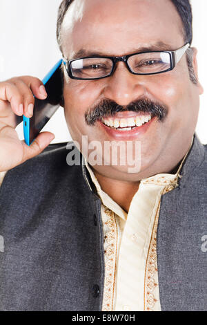 Well-groomed Indian man holding his phone on the eye level and sadly ...