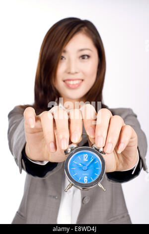 Young business woman holding a alarm clock Stock Photo - Alamy