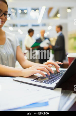 Close-up of young businesswoman typing on keyboard of laptop at table ...